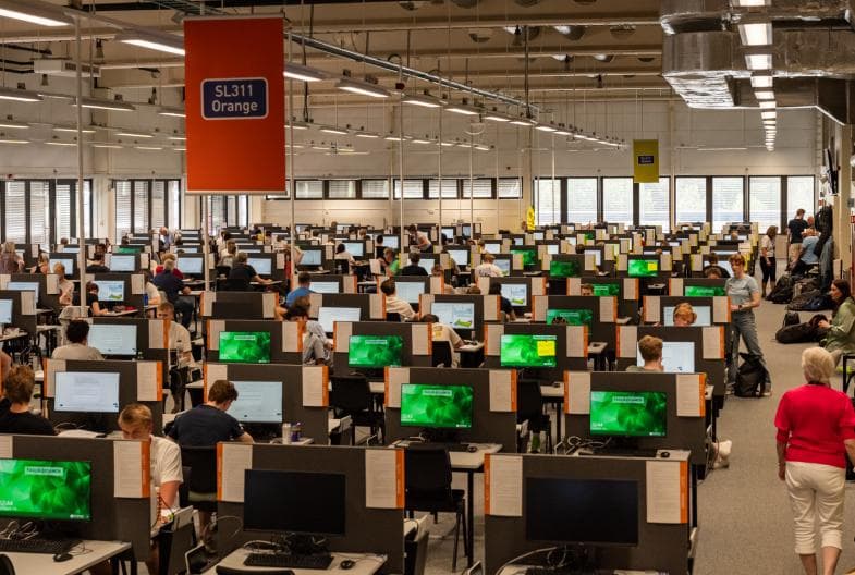Stor sal med pulter og datamaskiner og studenter